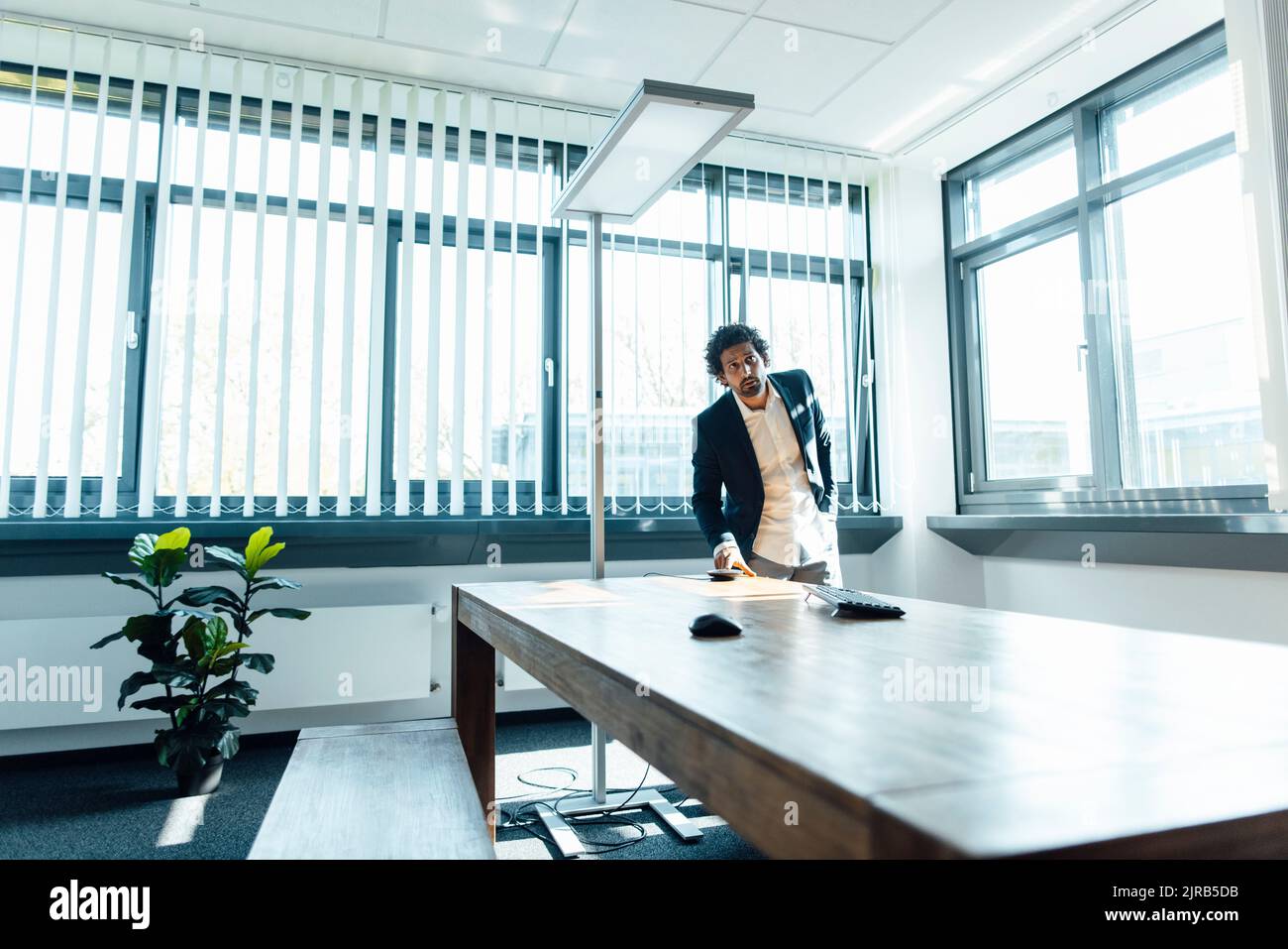 Businessman standing by desk at workplace Stock Photo - Alamy
