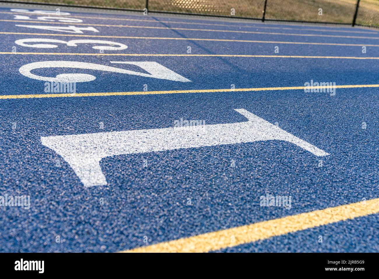Inspiring close up of a new blue running track with yellow lane lines ...