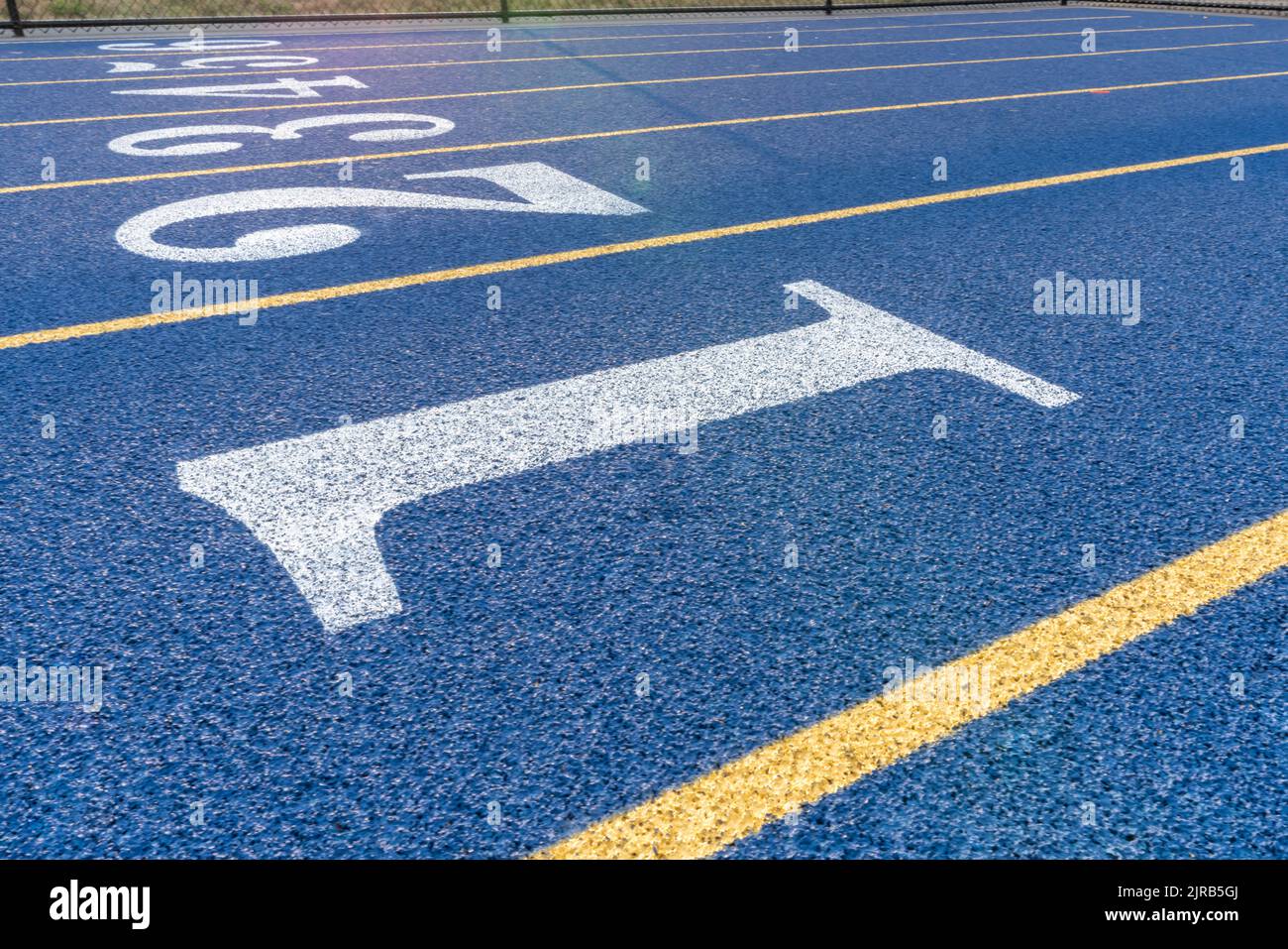 Inspiring close up of a new blue running track with yellow lane lines ...