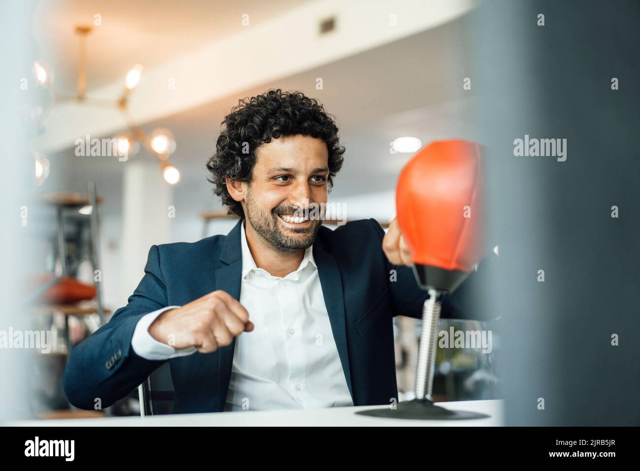 Smiling businessman punching speed bag at workplace Stock Photo - Alamy