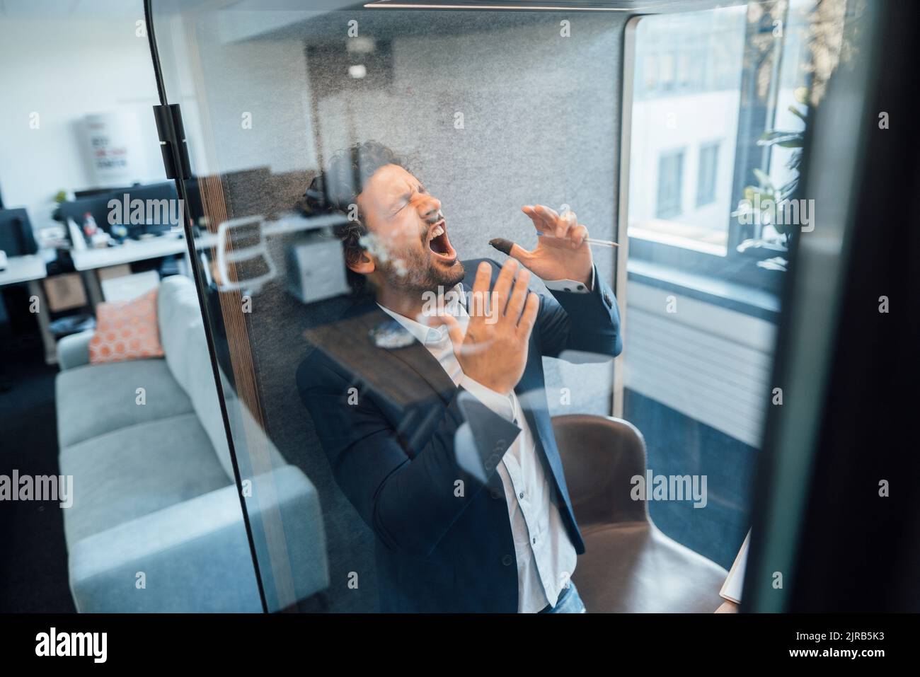Angry businessman shouting in soundproof cabin at office Stock Photo ...
