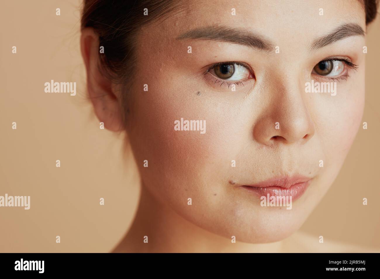 Portrait of young asian woman looking in camera against beige background Stock Photo - Alamy