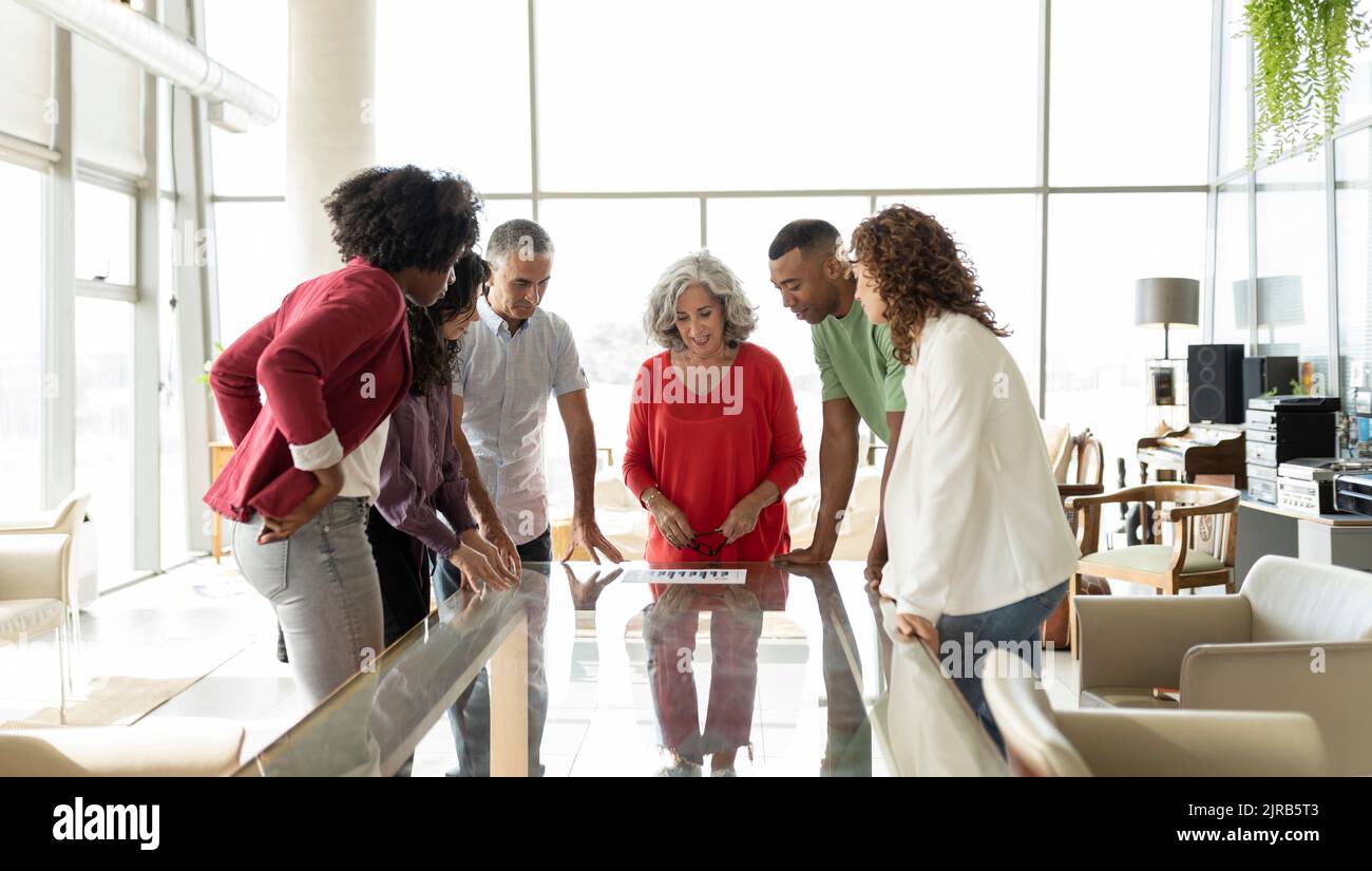 Senior businesswoman discussing over document with colleagues at desk ...