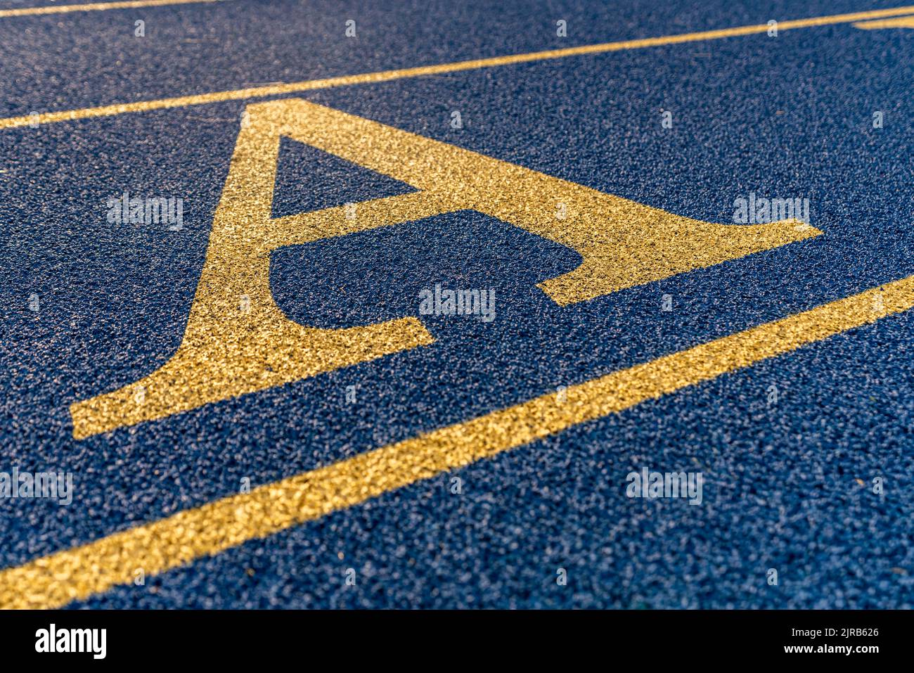 Close up the letter, initial A on a new blue running track with yellow ...