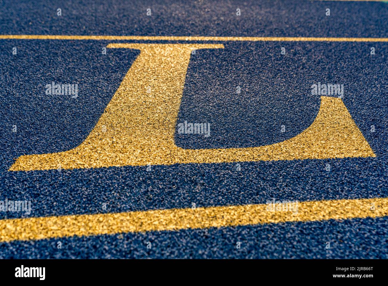 Close up the letter, initial L on a new blue running track with yellow ...