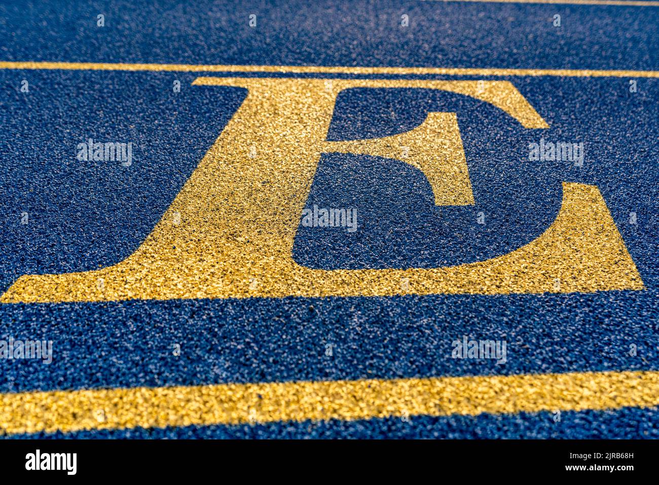 Close up the letter, initial E on a new blue running track with yellow ...