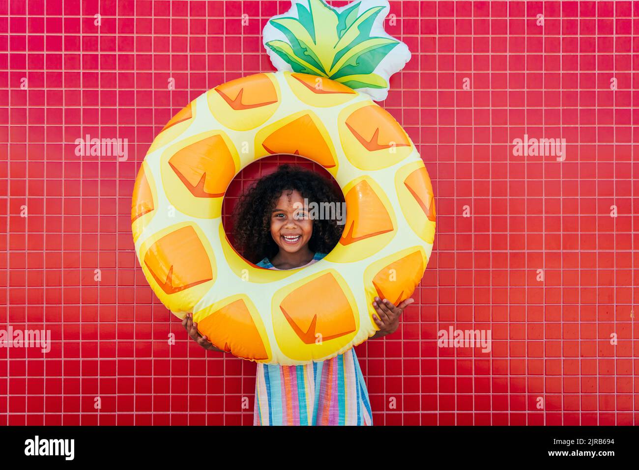 Cute girl holding inflatable ring standing in front of wall Stock Photo ...