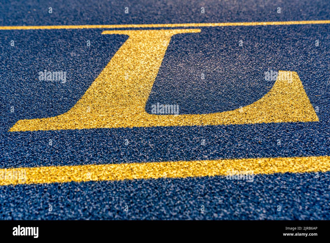 Close up the letter, initial L on a new blue running track with yellow ...