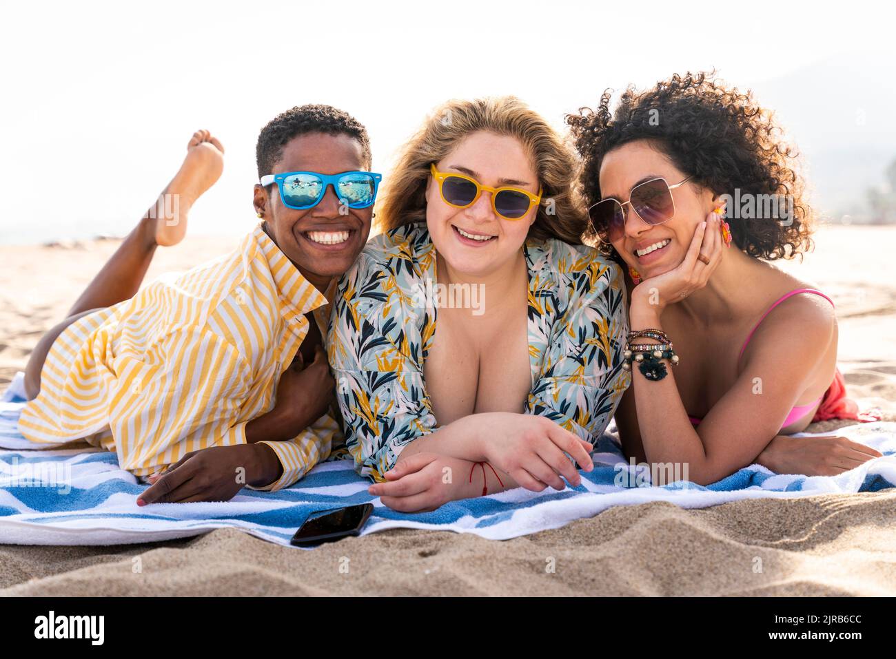 Friends wearing sunglasses lying down on towel at beach Stock Photo - Alamy