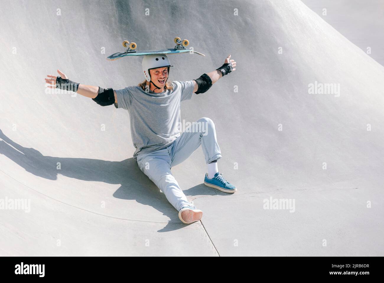 Happy man balancing skateboard on head in skate park Stock Photo - Alamy