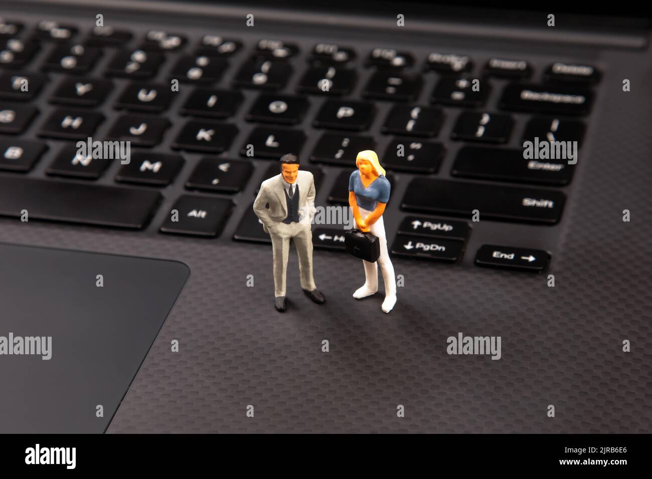 miniature people. figures of business people stand on a laptop keyboard ...