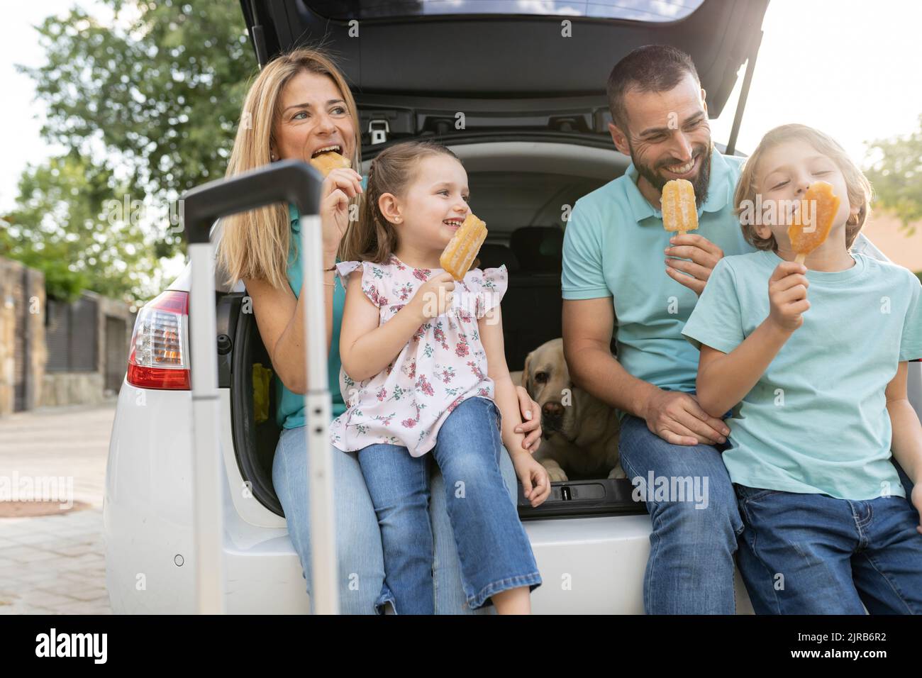 Happy family eating ice pops sitting in car trunk Stock Photo - Alamy