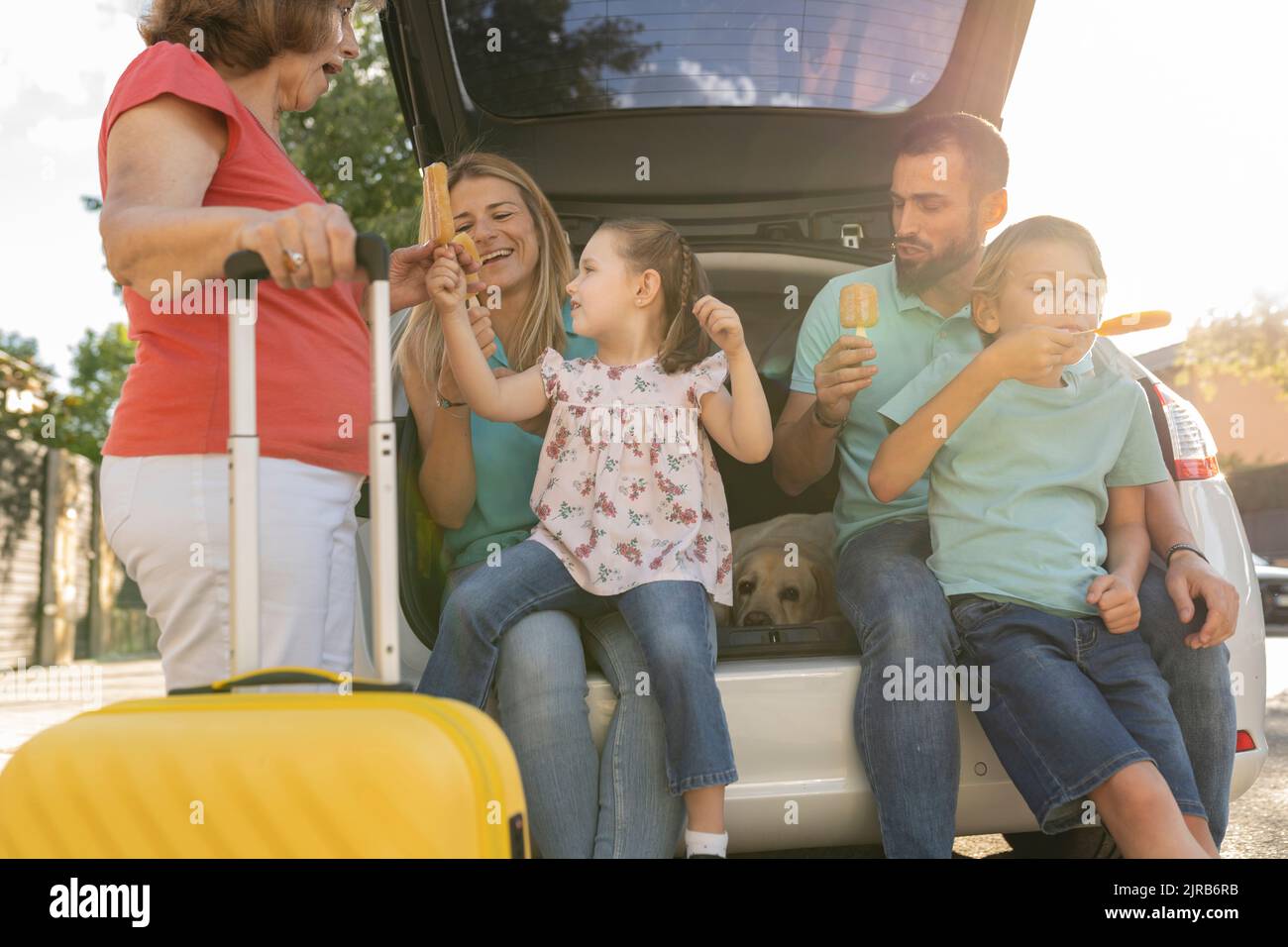 Happy family eating ice pops sitting at back of car Stock Photo - Alamy