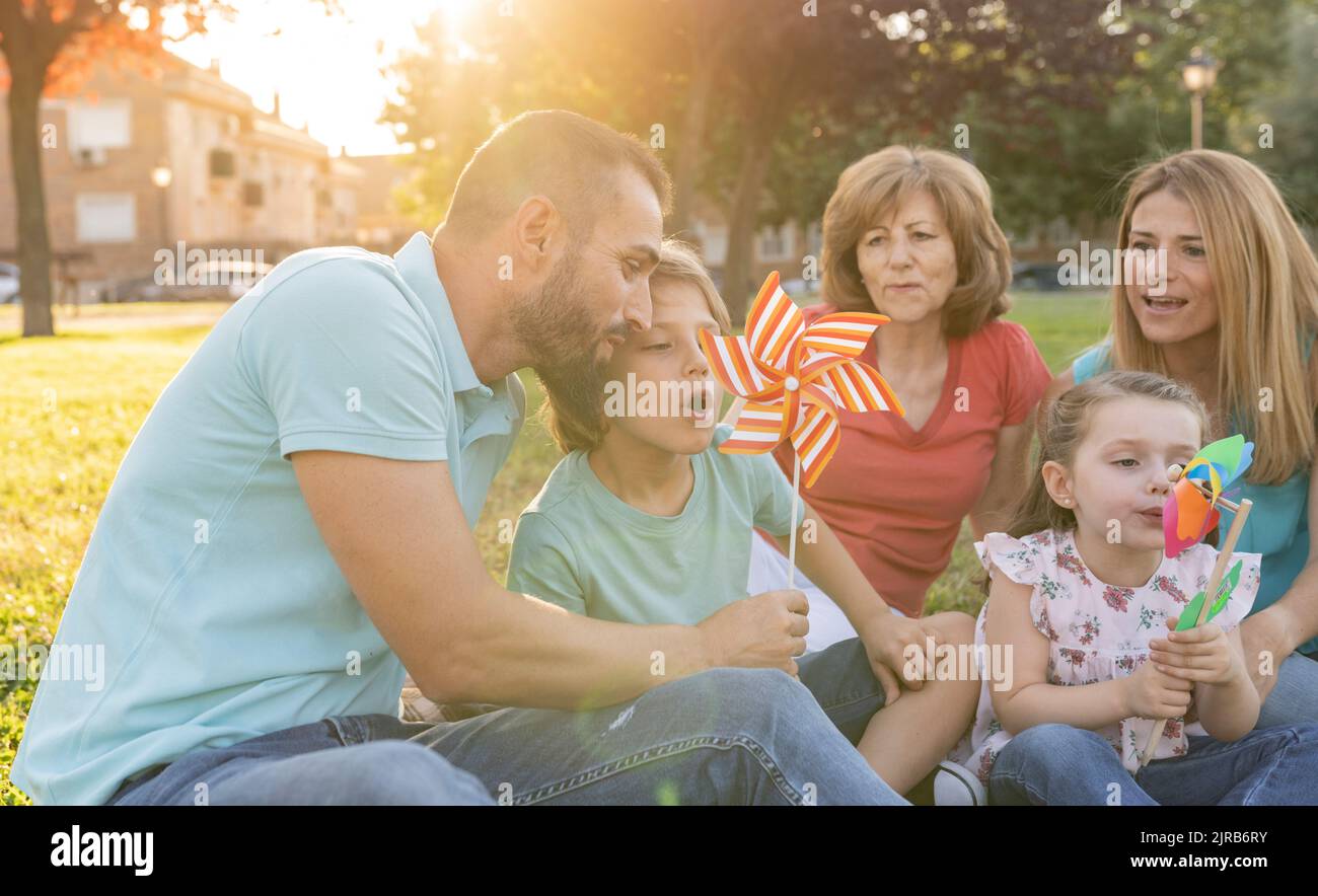Family playing with pinwheels sitting at park Stock Photo - Alamy