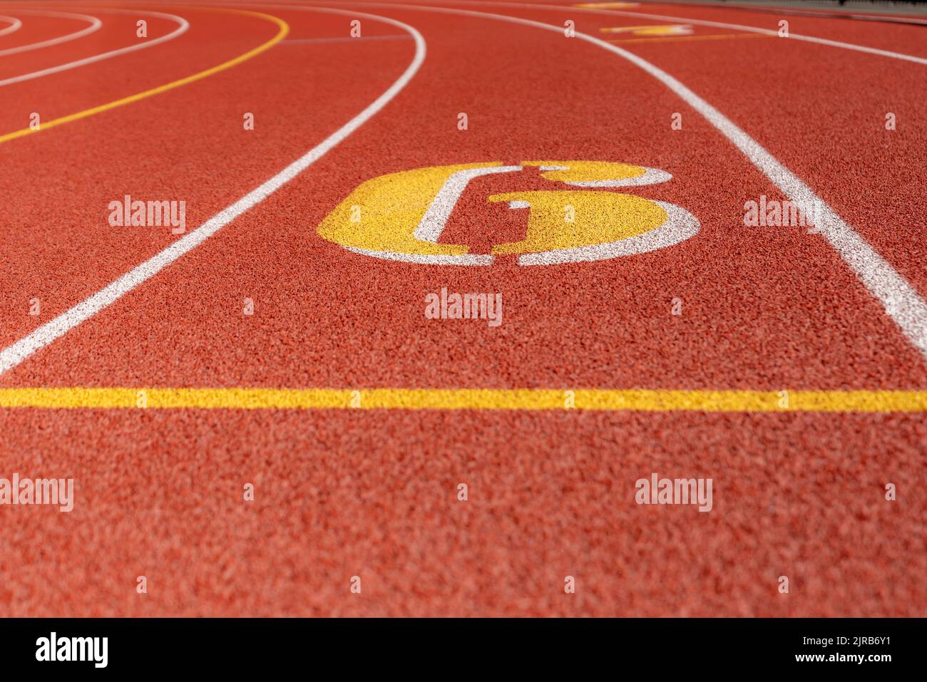 Close up lane number 6 on a new red running track with white lane lines ...
