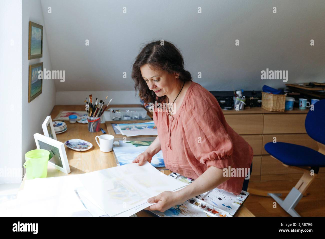 Artist standing at table looking at watercolor paintings Stock Photo ...
