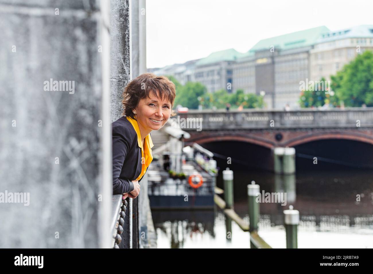 Smiling mature woman leaning out of window Stock Photo - Alamy
