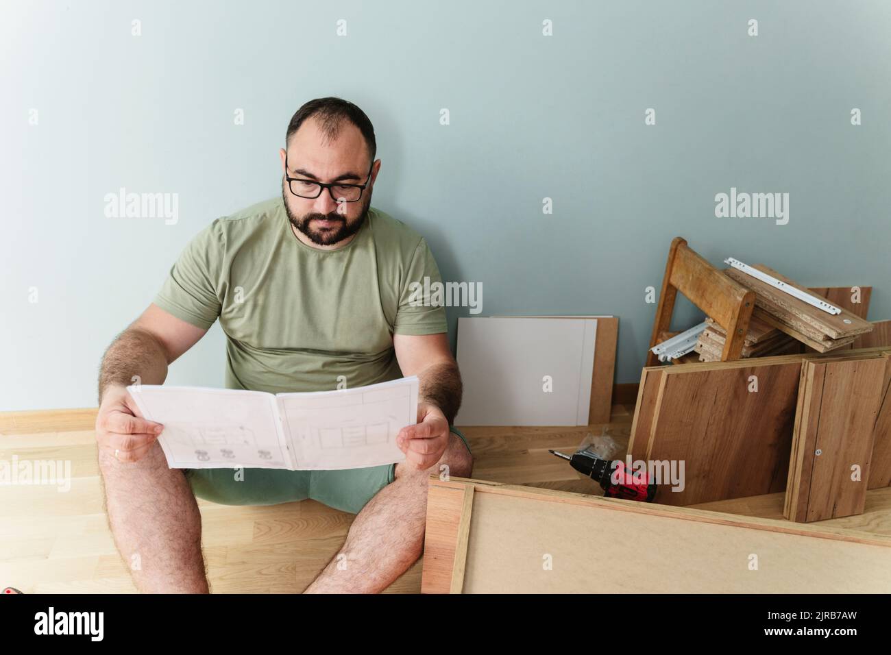 Man reading instruction manual sitting on floor at home Stock Photo - Alamy
