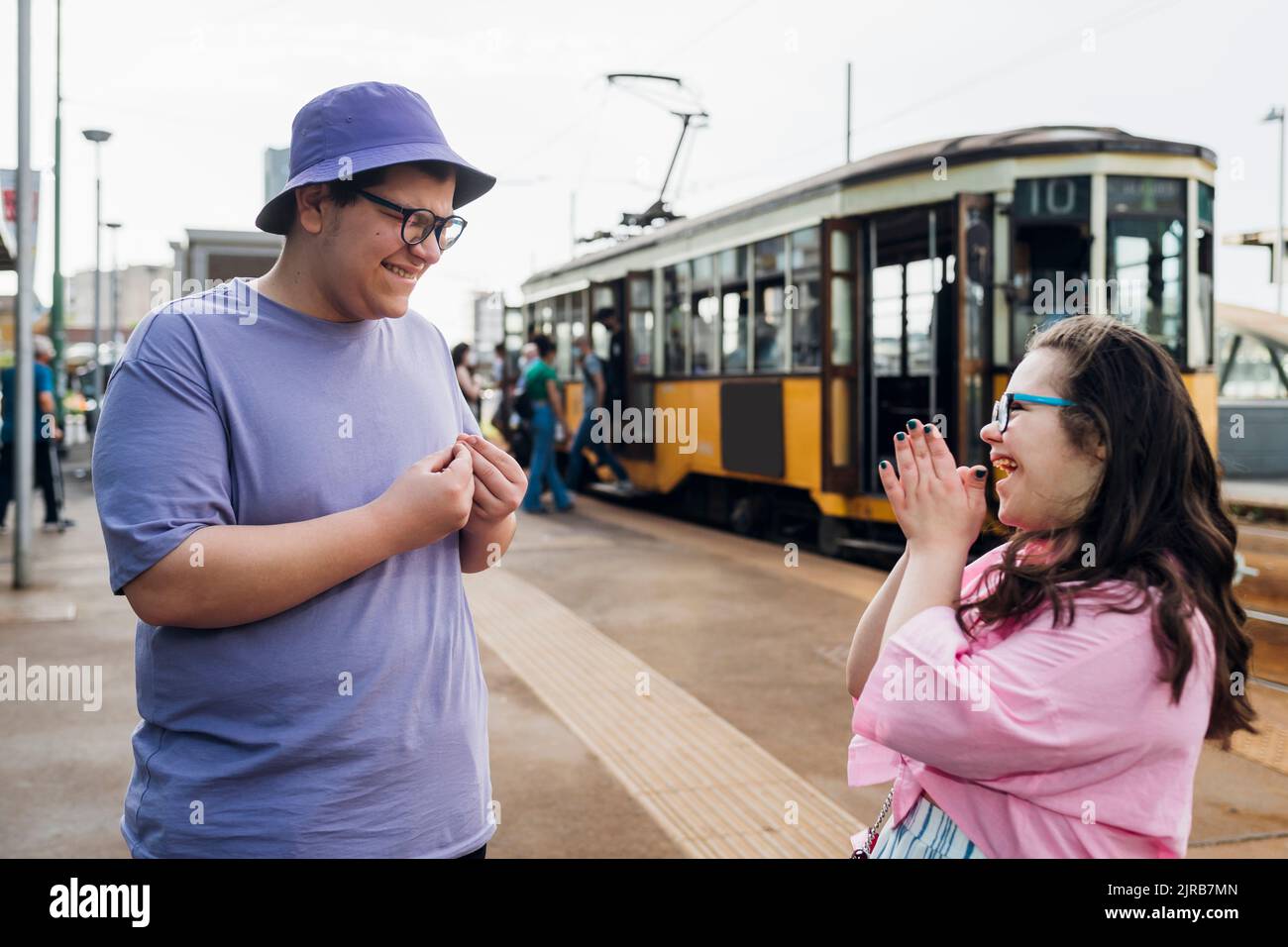 Happy brother and sister laughing at tram station in city Stock Photo ...