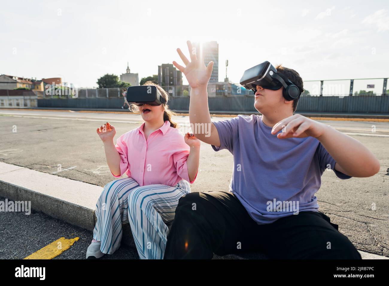 Teenage girl and boy wearing VR goggles on city street Stock Photo - Alamy