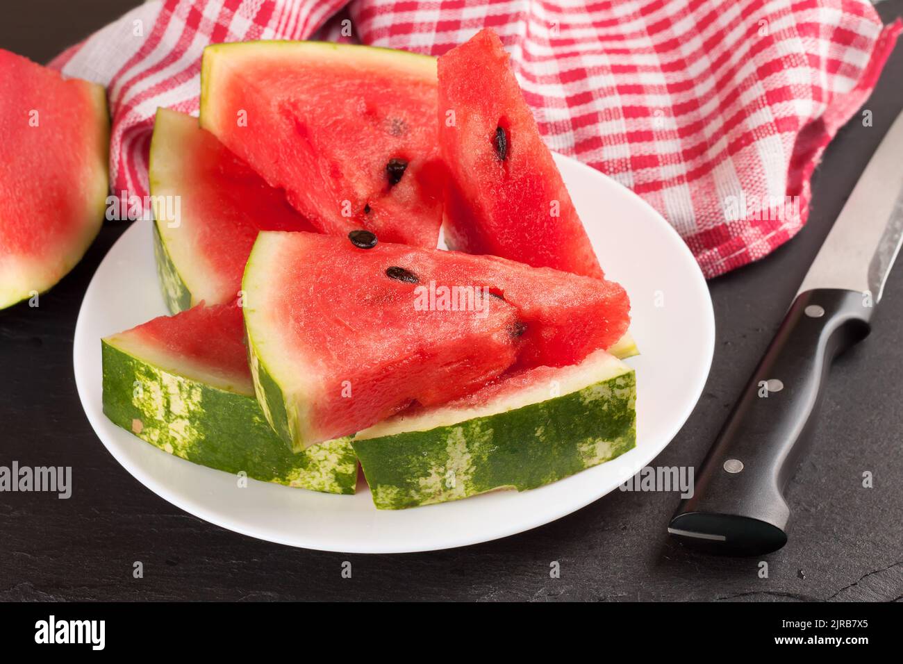 Triangle slices of watermelon on the plate on black slate background ...
