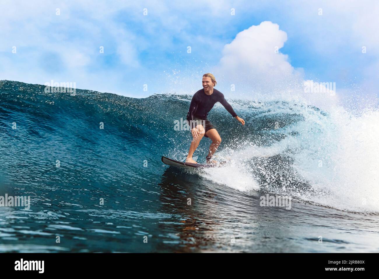 Happy man surfing on sea in front of cloudy sky Stock Photo - Alamy