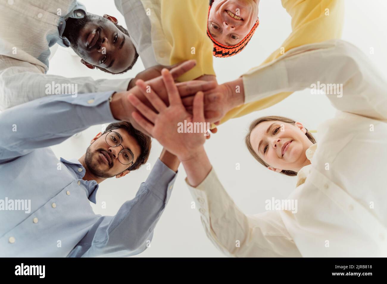 Smiling colleagues with hands stacked having team building training ...