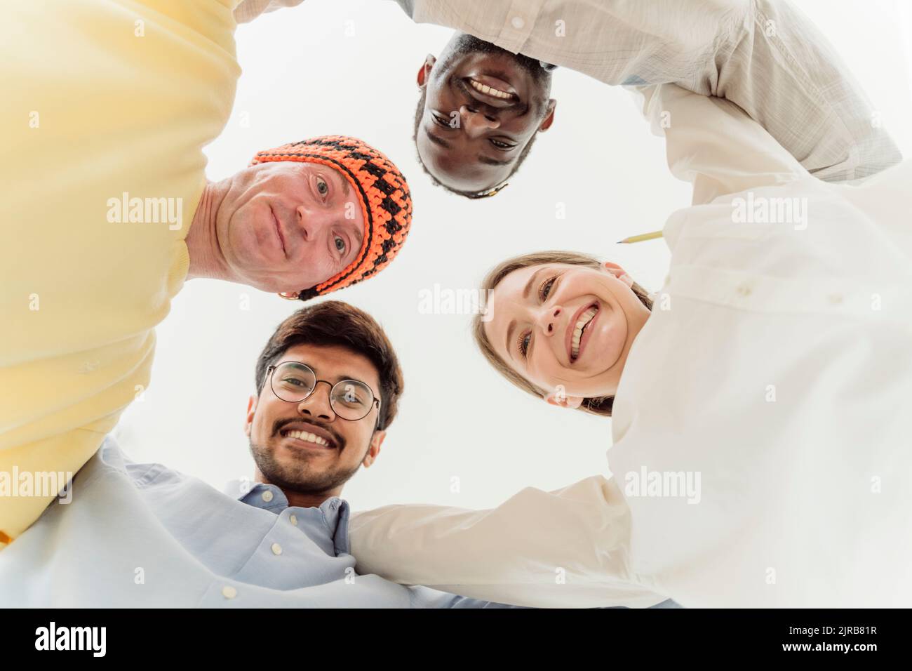 Happy multiracial colleagues huddling together in team building ...