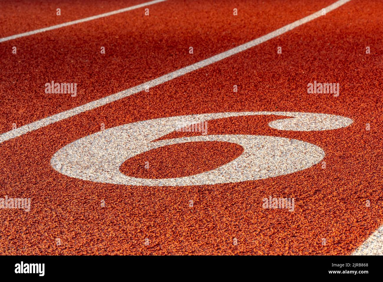 Close up lane number 6 on a new red running track with white lane lines ...