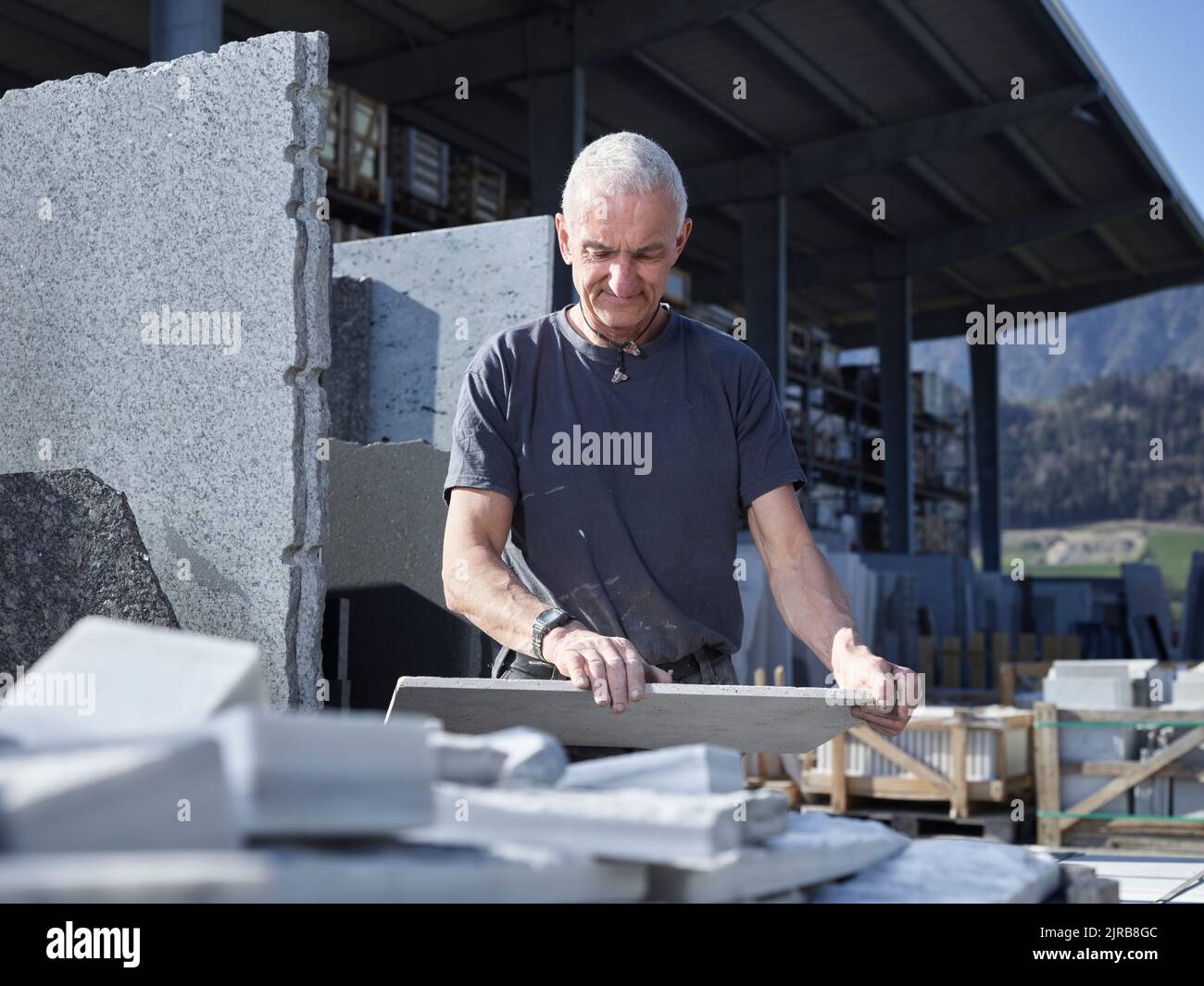 Smiling stonemason examining natural stone slab at workshop Stock Photo ...