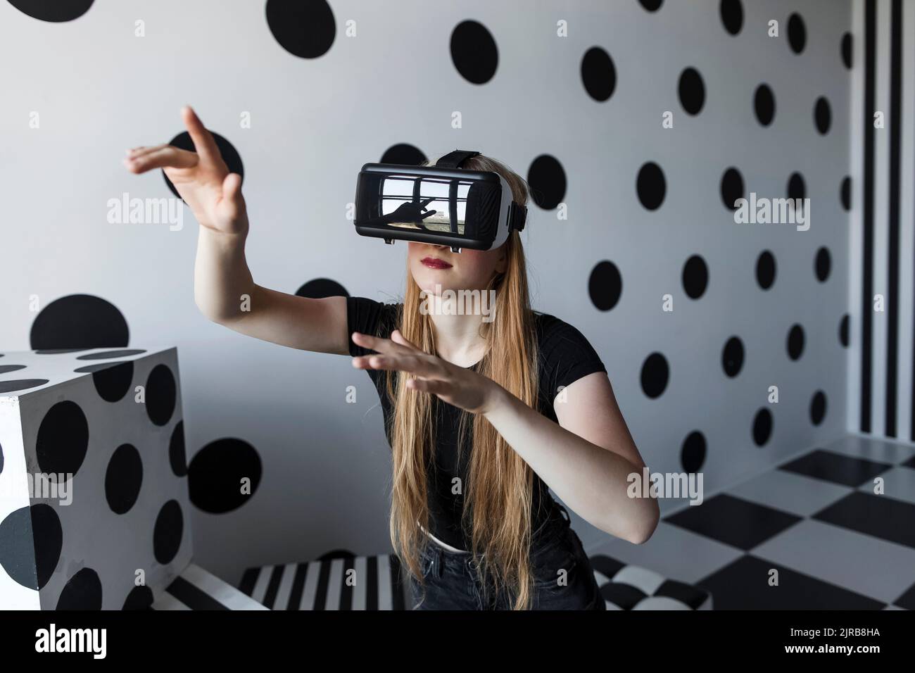 Girl with long hair wearing virtual reality headset by dotted wall ...
