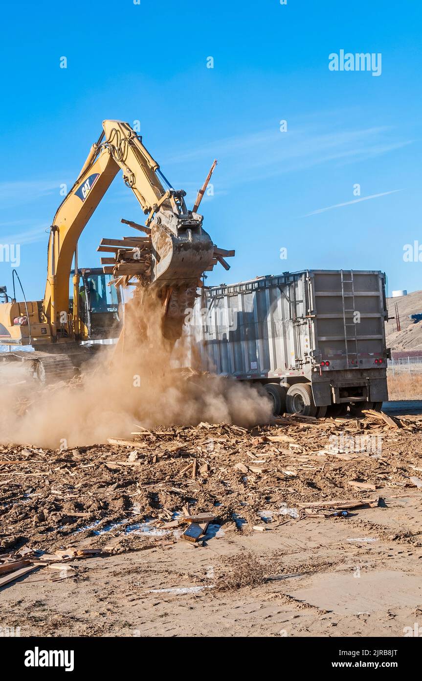 A power shovel loads solid waste into a large truck container for ...