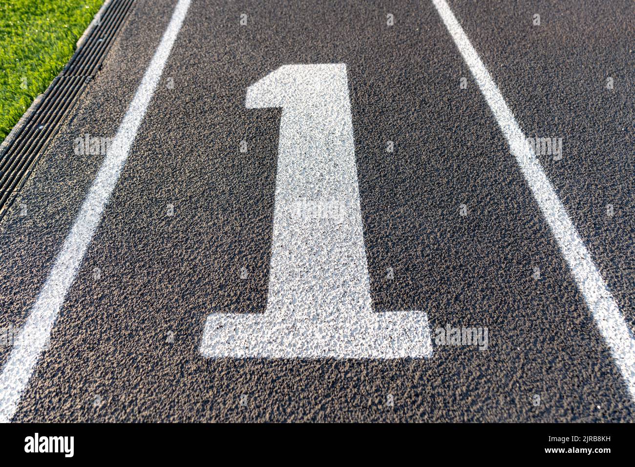 Close up lane number one, 1, on a new black running track with white ...