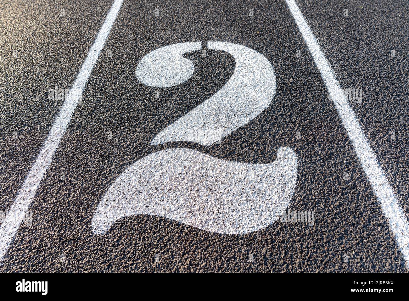Close up lane number two, 2, on a new black running track with white ...