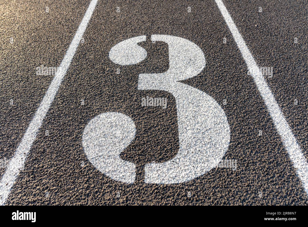 Close up lane number three, 3, on a new black running track with white ...
