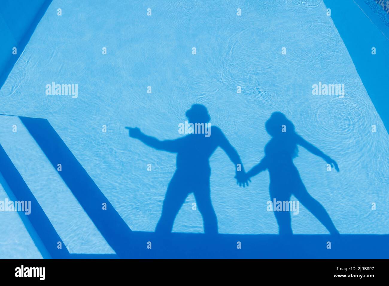 Shadow of man holding hand of woman seen on water of pool Stock Photo ...