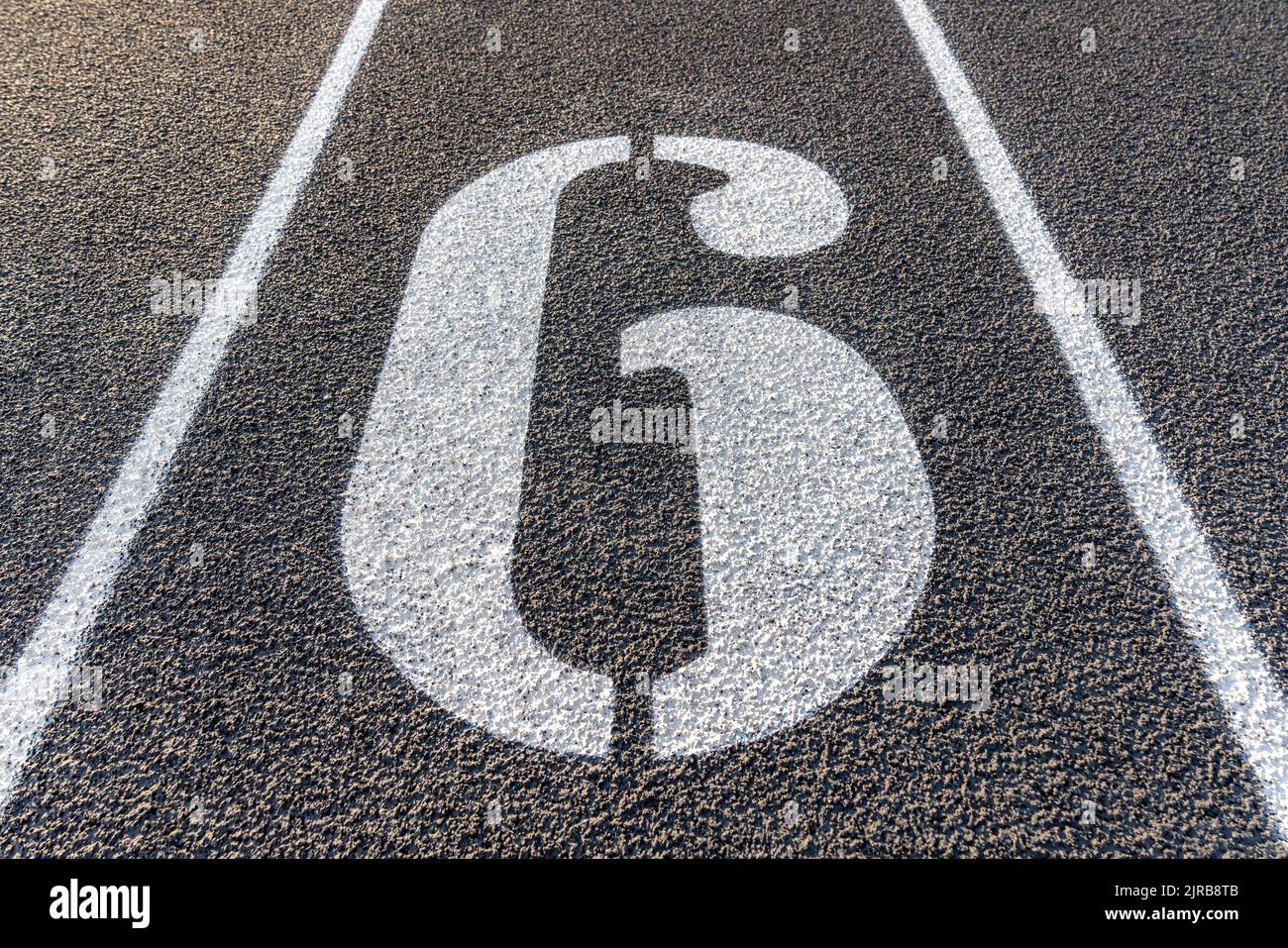 Close up lane number six, 6, on a new black running track with white ...