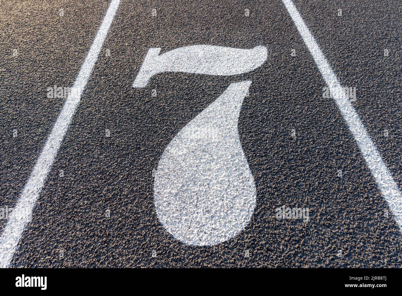 Close up lane number seven, 7, on a new black running track with white ...