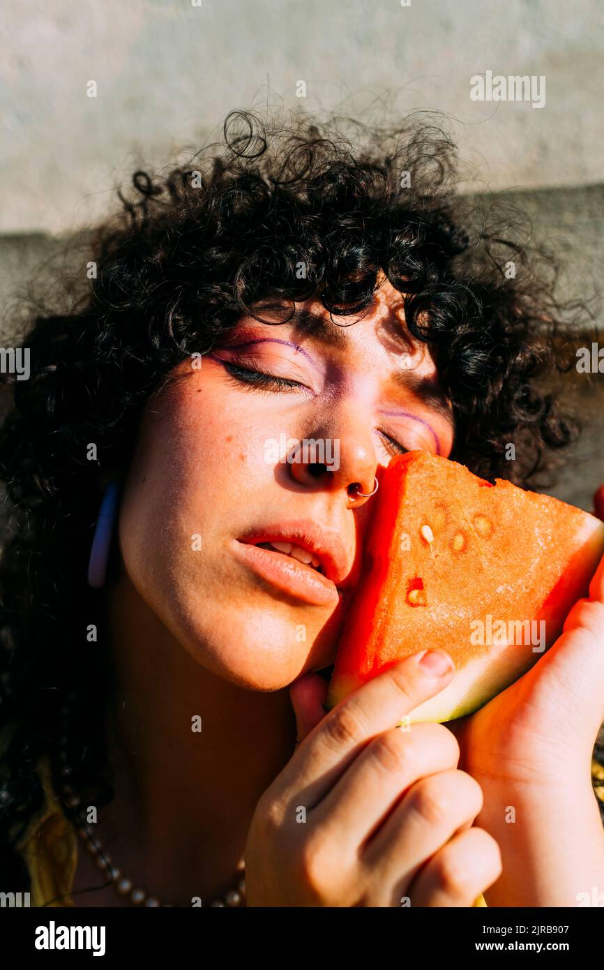 Woman touching watermelon slice on cheek Stock Photo - Alamy
