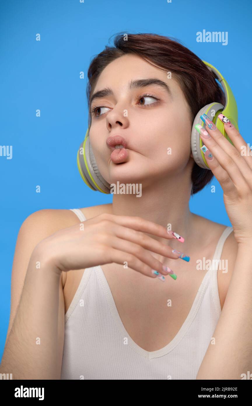 Cute young brunette making fish lips while listening music using ...