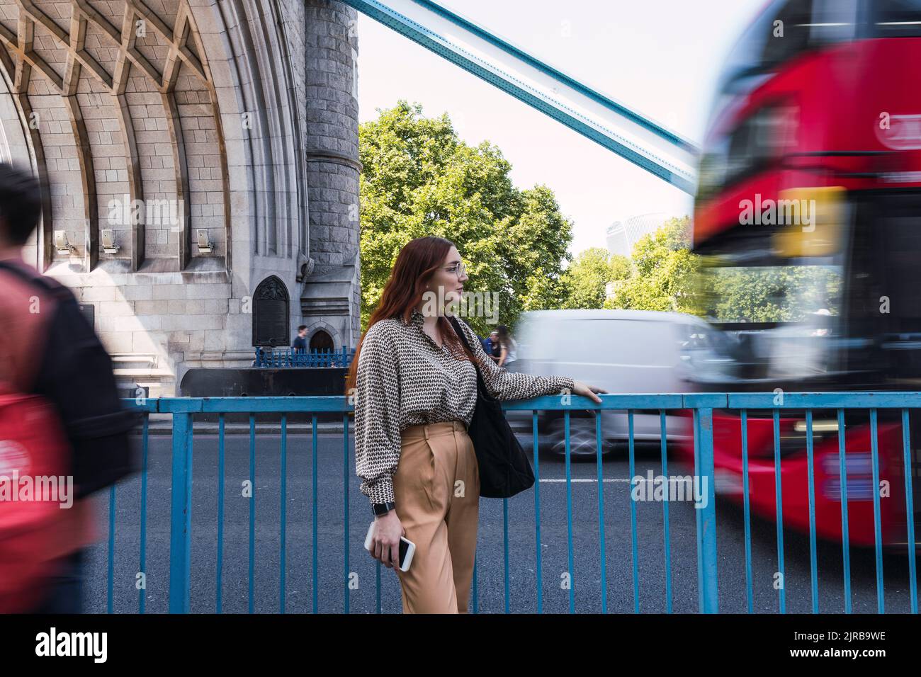 Young woman standing by railing at Tower Bridge, London, England Stock ...