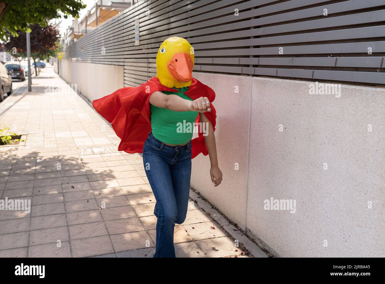 Young woman wearing duck mask running by wall Stock Photo - Alamy