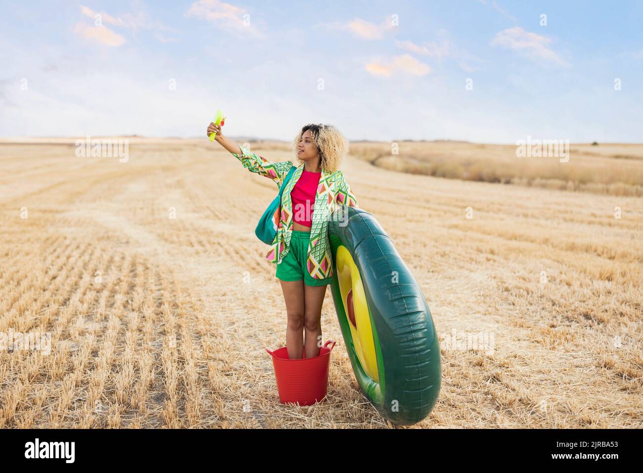 Woman standing in bucket with avocado shaped inflatable ring looking at ...