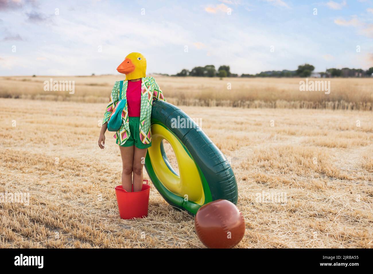 Woman wearing duck mask standing in bucket with inflatable ring at ...