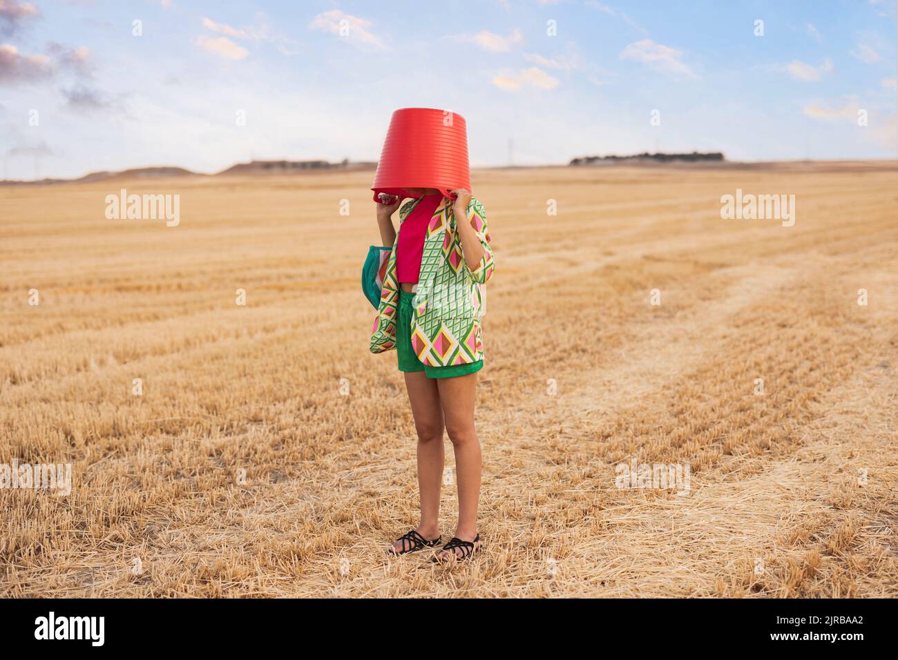 Woman covering face with bucket at field Stock Photo - Alamy