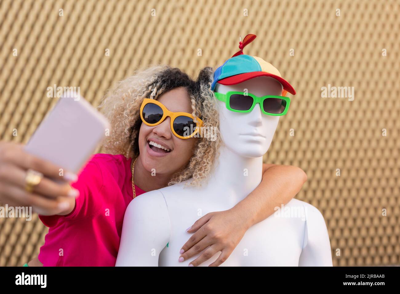 Happy woman taking selfie through smart phone with mannequin in front ...
