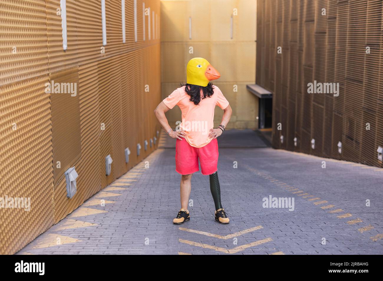 Man with prosthetic leg wearing duck mask standing on road Stock Photo ...