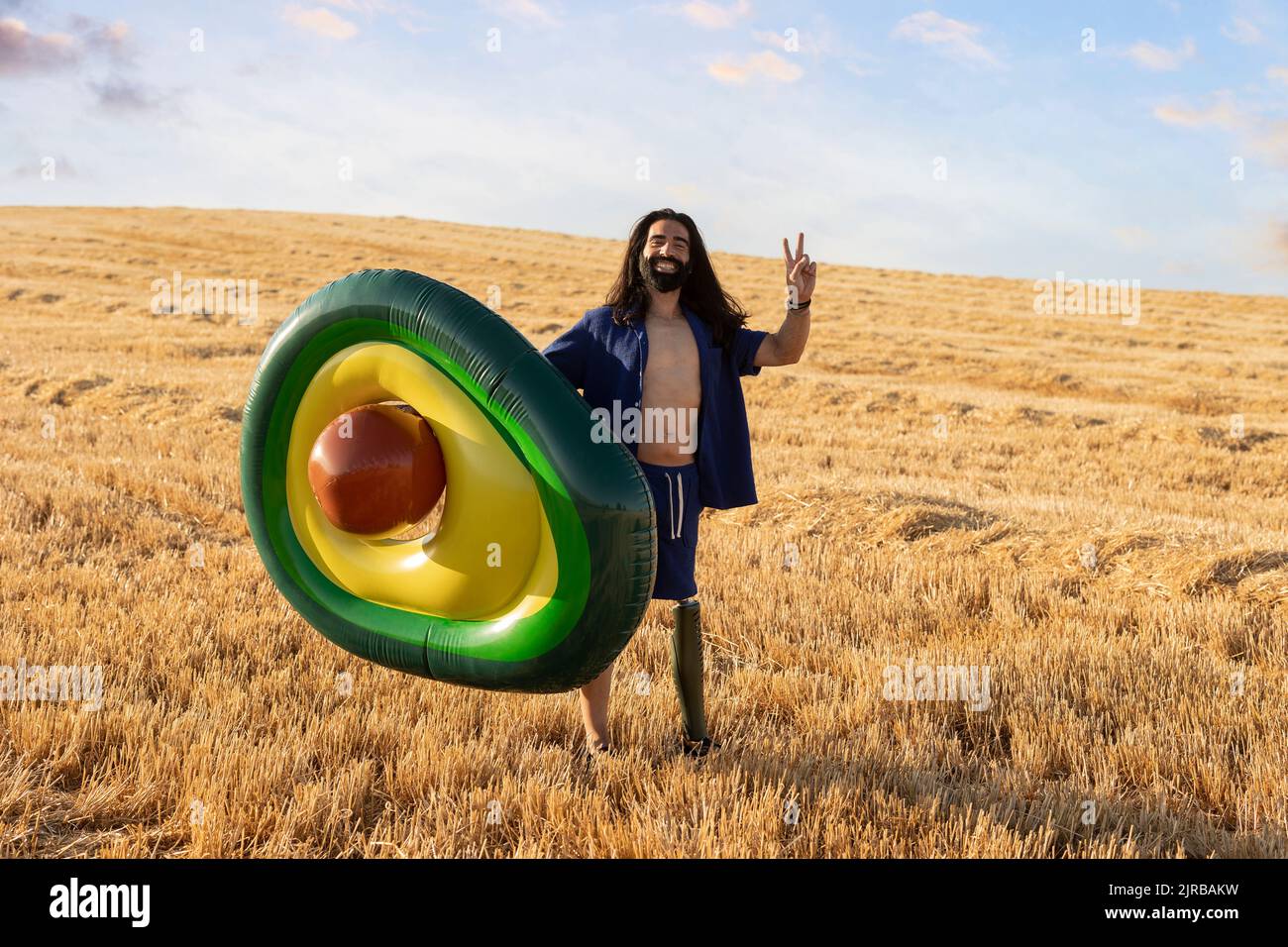 Smiling man with prosthetic leg holding avocado shaped inflatable ring ...