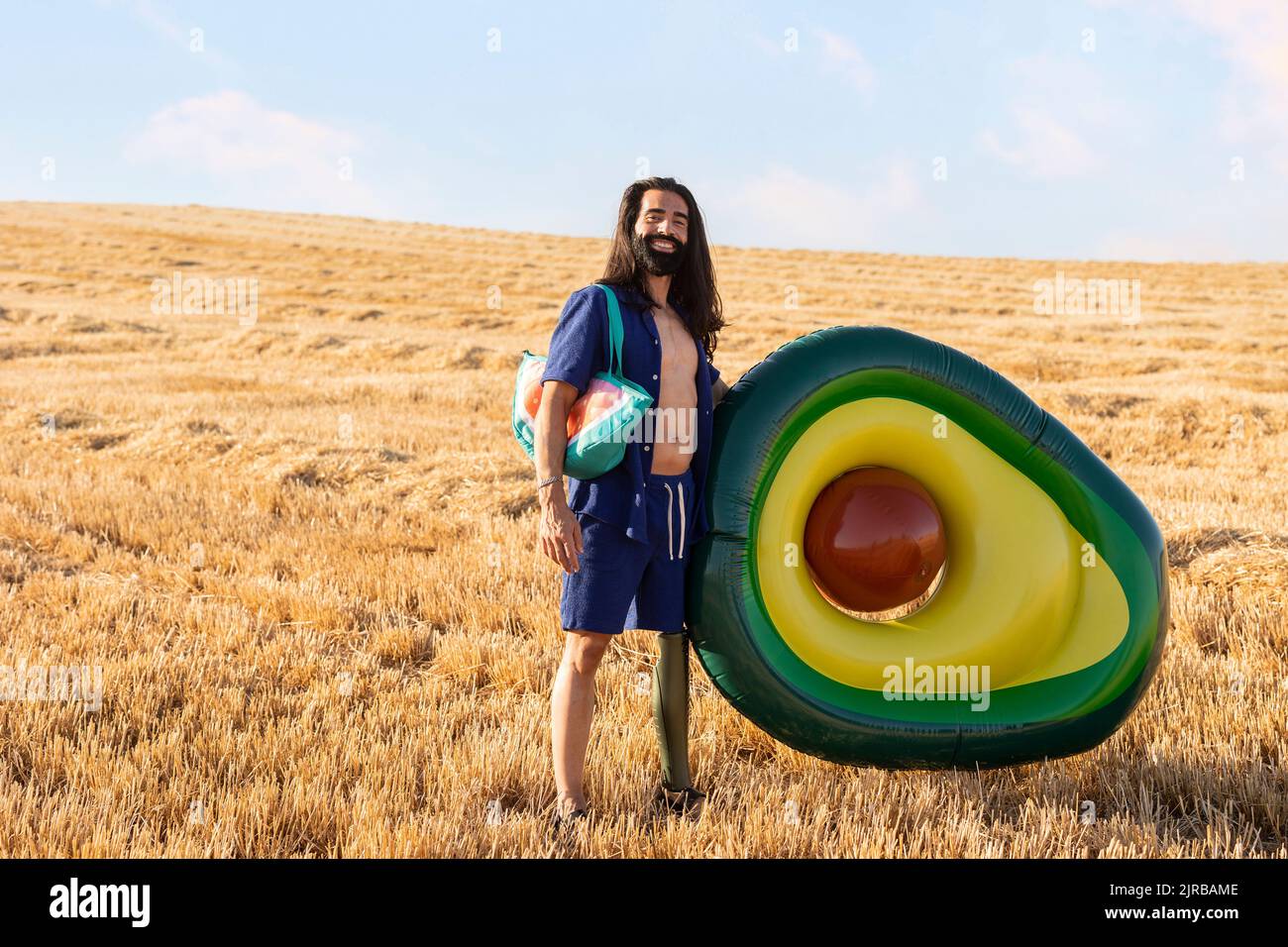 Smiling bearded man with prosthetic leg carrying bag by avocado shaped ...