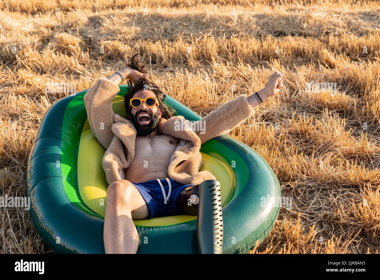 Happy bearded man with prosthetic leg lying on inflatable ring at field ...